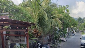Rua com placa indicando 'Batu Nunggul Beach' e área coberta com uma scooter estacionada.