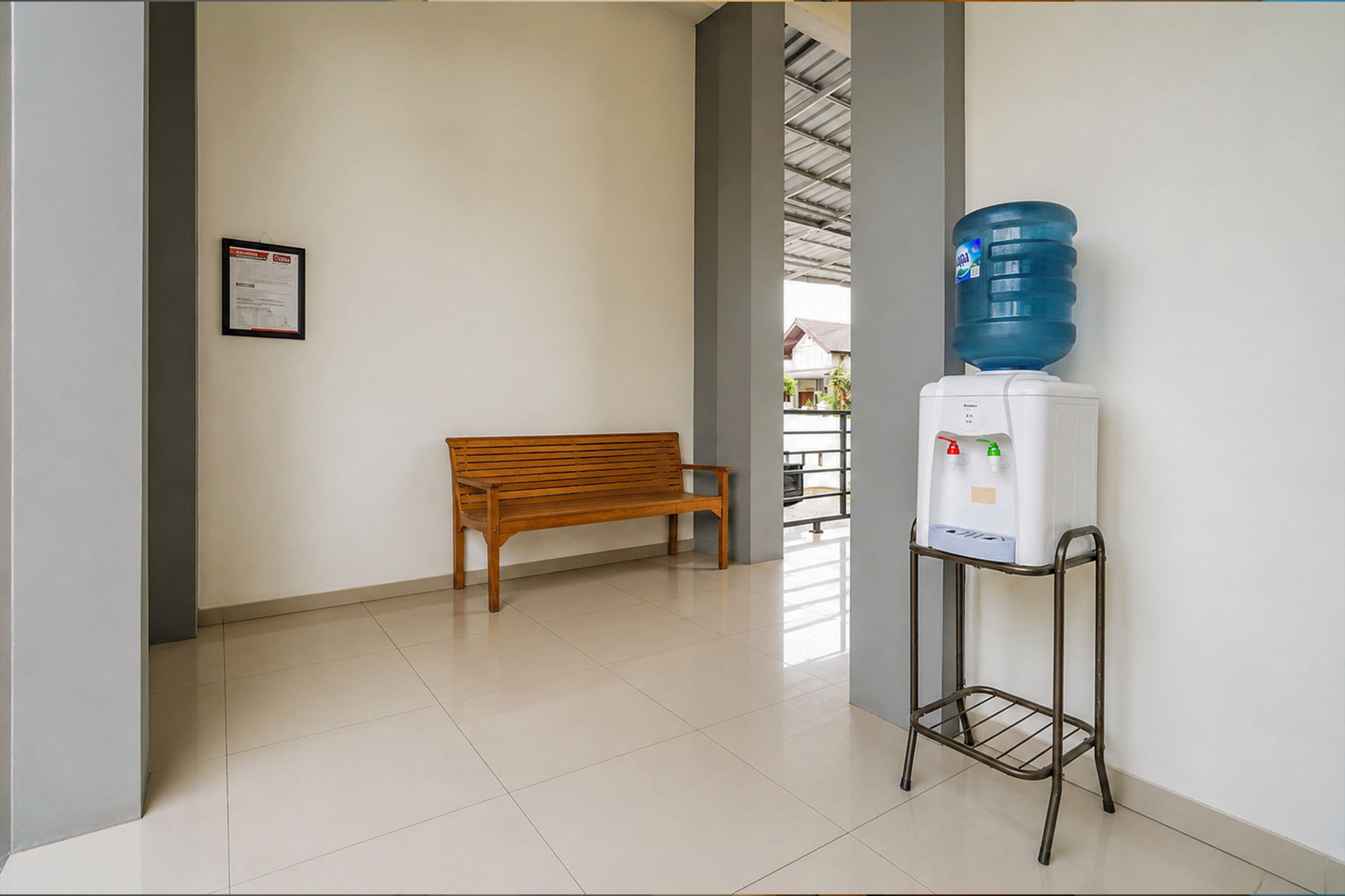 Corredor com um banco de madeira, um bebedouro e uma garrafa grande de água em um suporte.
