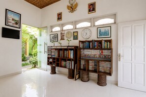 Um quarto amplo com uma grande estante, um relógio de parede e quadros emoldurados.