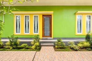 Um edifício moderno com fachada verde, janelas emolduradas em amarelo e porta de madeira.