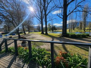 Um parque com um deck de madeira, um lago e árvores.