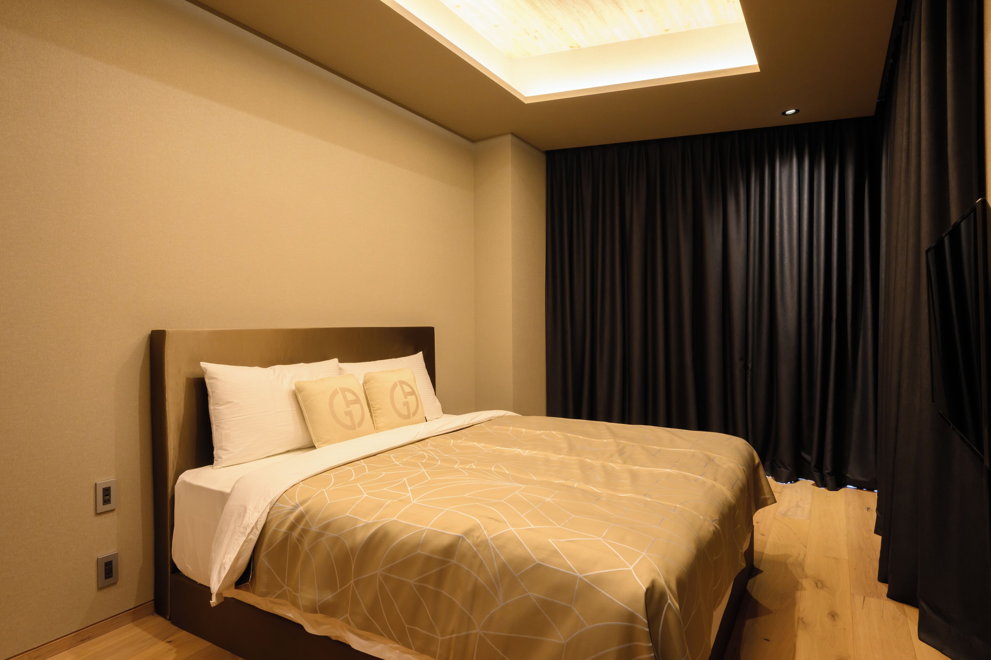Quarto de hotel com uma cama, uma luminária no teto e uma cortina preta.