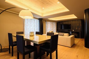 Uma sala de estar moderna com área de jantar, piso de madeira e televisão de tela plana.