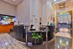 Uma área de recepção de hotel com balcão, relógio e mapa na parede.