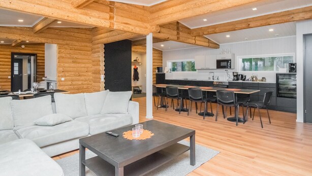 Interior de uma cabana de troncos moderna, com sala de estar, área de refeições e cozinha.