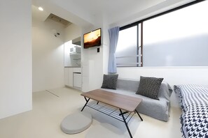 Quarto moderno e minimalista com sofá, mesinha e televisão fixada na parede.