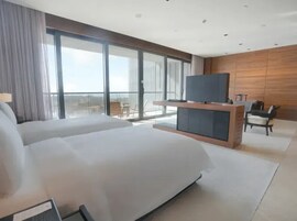 Quarto de hotel moderno com uma cama grande, televisão e varanda com vista.
