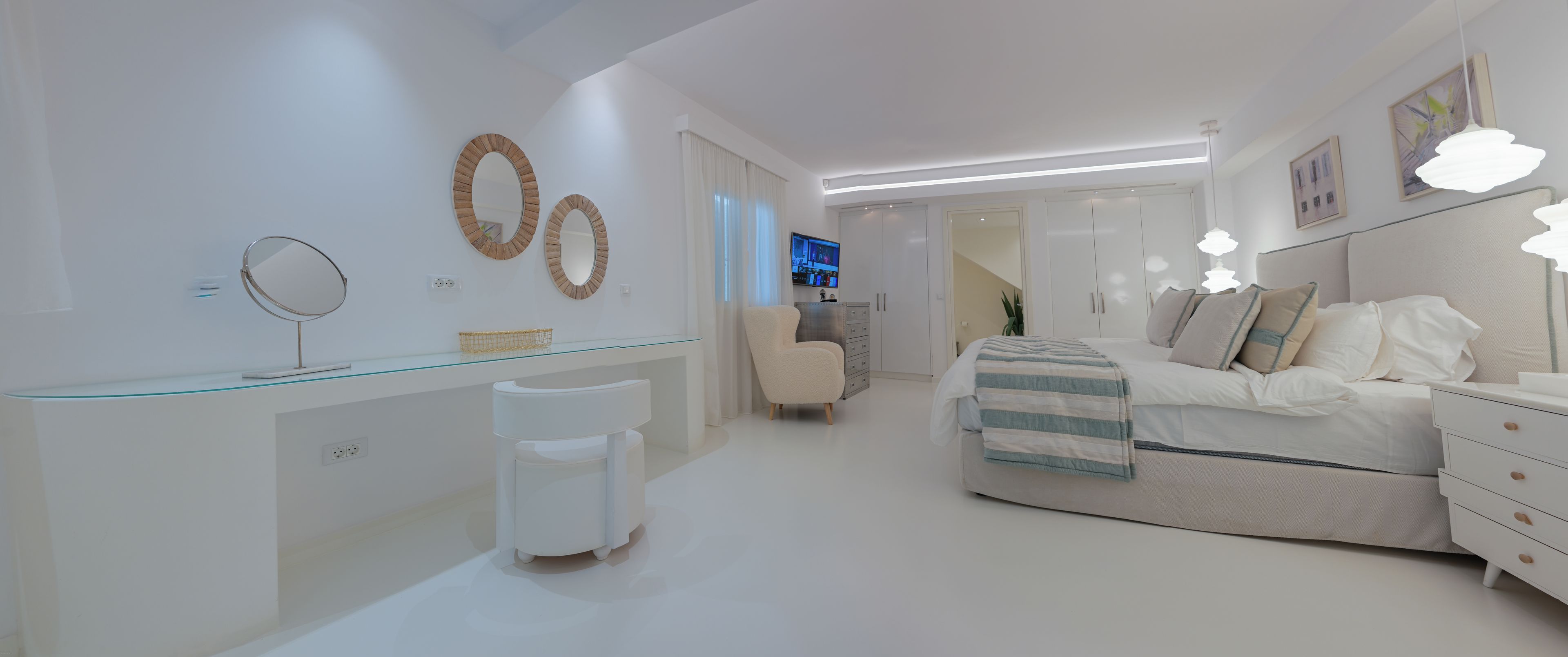 Quarto moderno com cama, mesas de cabeceira, televisão e espelho.