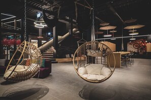 Um interior moderno com cadeiras penduradas, uma escada e um espaço bar.