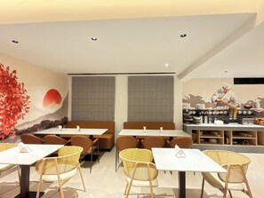 Interior de restaurante com boxes, mesas e um chef preparando comida.