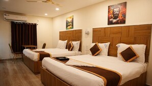 Quarto de hotel com duas camas, cabeceiras de madeira e um ventilador de teto.