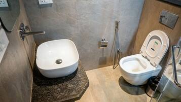 Casa de banho moderna com lavatório branco, sanita e chuveiro.