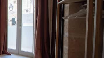 Quarto com piso de azulejos, guarda-roupa de madeira e porta de vidro deslizante que dá para o exterior.