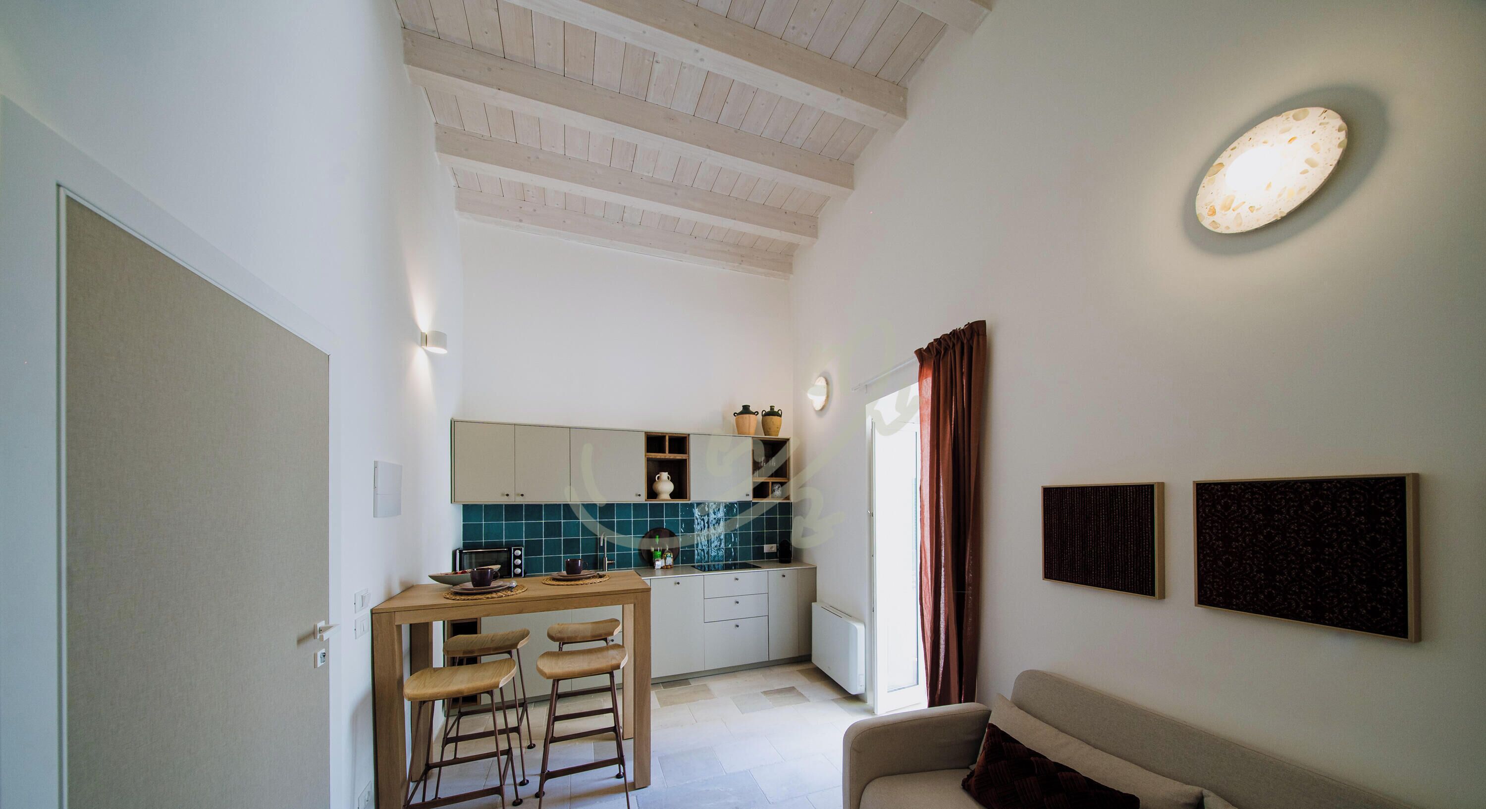 Cozinha compacta com área de refeições, micro-ondas embutido e janela com cortinas.