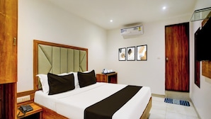 Quarto de hotel com cama, mesas de cabeceira, telefone, ar-condicionado fixado na parede e obras de arte emolduradas.