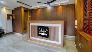 Bancada de recepção com uma placa indicando serviço da empresa, um ventilador de teto e um painel de parede de madeira.