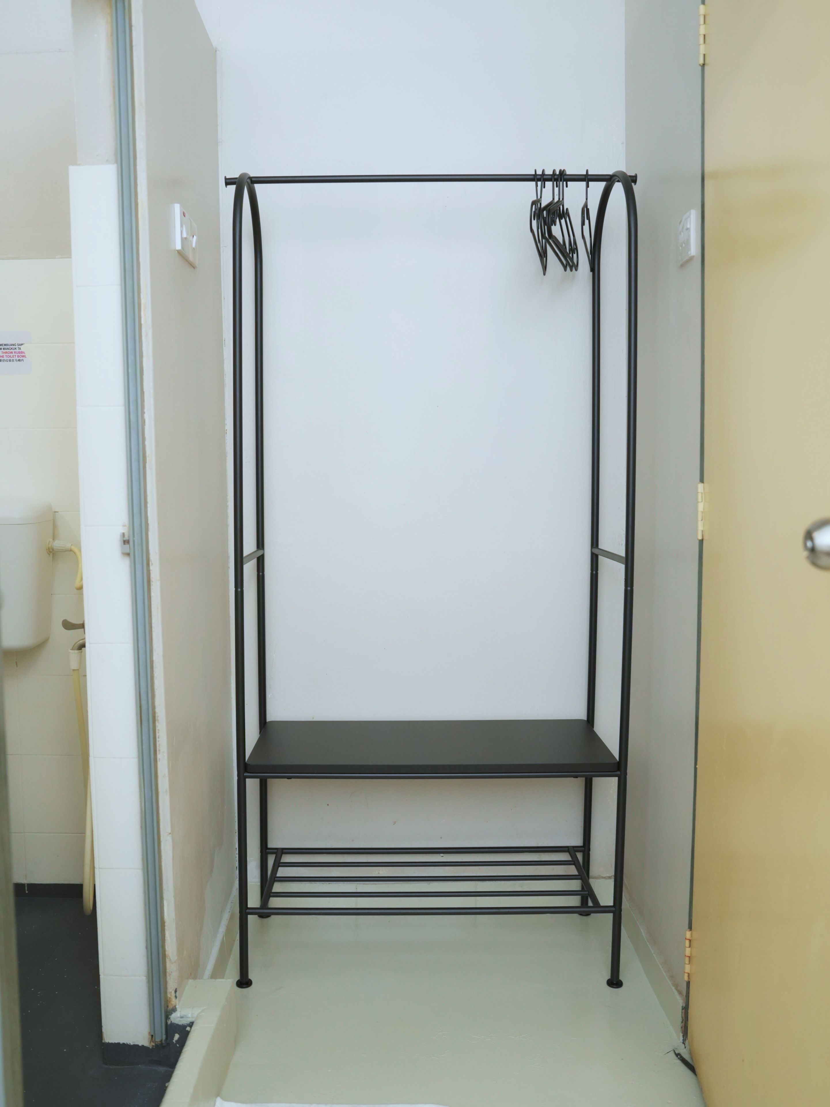 Estrutura de cama de metal com colchão em quarto com paredes brancas e porta.