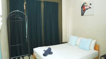 Quarto com cama, porta-toalhas suspenso e ar-condicionado fixado na parede.