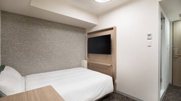 Quarto de hotel com cama, televisão de tela plana na parede, porta e interruptor de luz.
