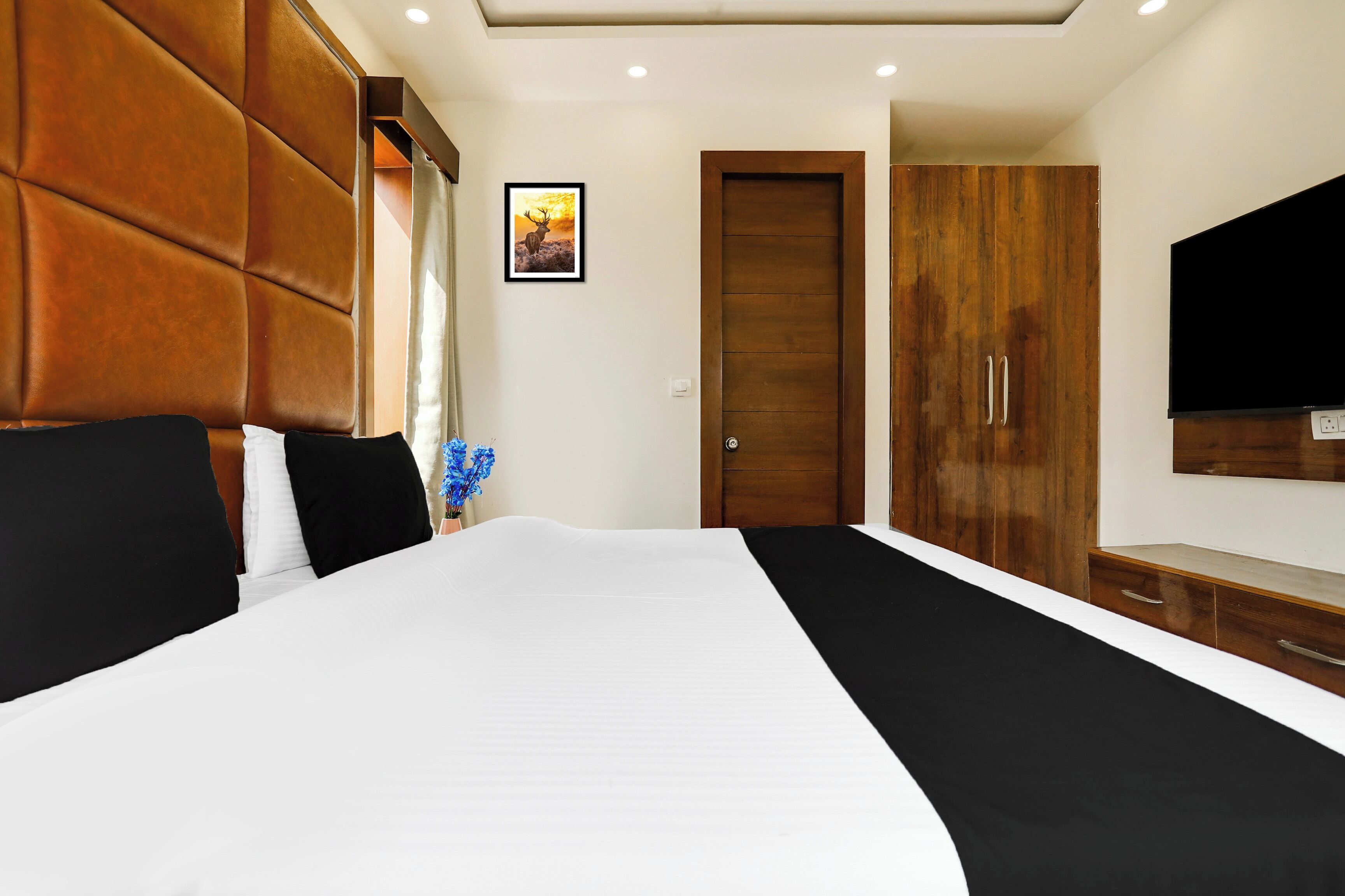 Quarto de hotel com uma cama grande, um guarda-roupa, uma televisão e uma porta.
