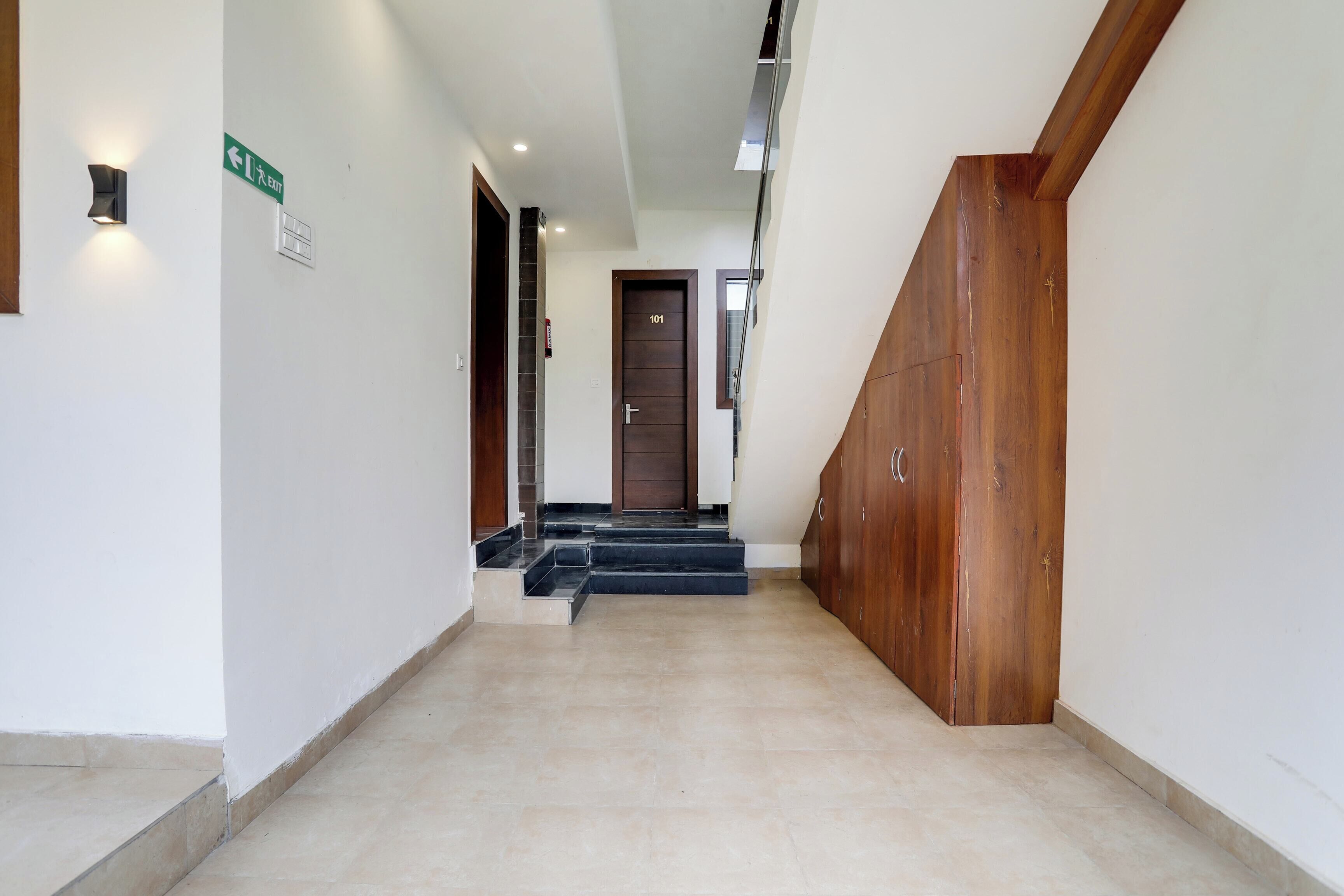 Um corredor com escadas de madeira que levam a uma porta com o número 101.