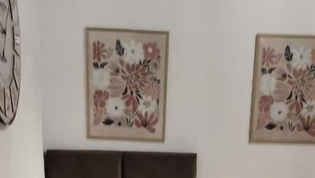 Cama bem arrumada com colcha marrom listrada e travesseiro branco, luminária de cabeceira e mesa de cabeceira com abajur.