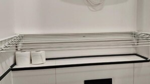 Quarto claro com varal embutido e espelho com moldura preta.