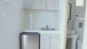 Uma cozinha compacta com máquina de lavar louça embutida, pia e bancada pequena.