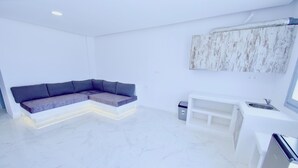 Uma sala de estar moderna com um sofá seccional, uma mesa de consola branca e um banco embutido.