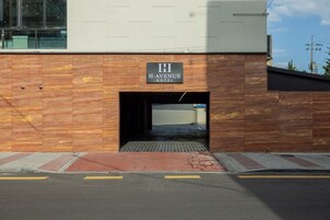Entrada de um hotel com uma placa indicando 'H. AVENUE HOTEL' e uma galeria coberta que dá acesso ao interior.