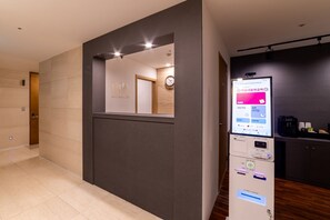 Uma área de recepção com um display digital, um relógio e uma porta que dá para um quarto.