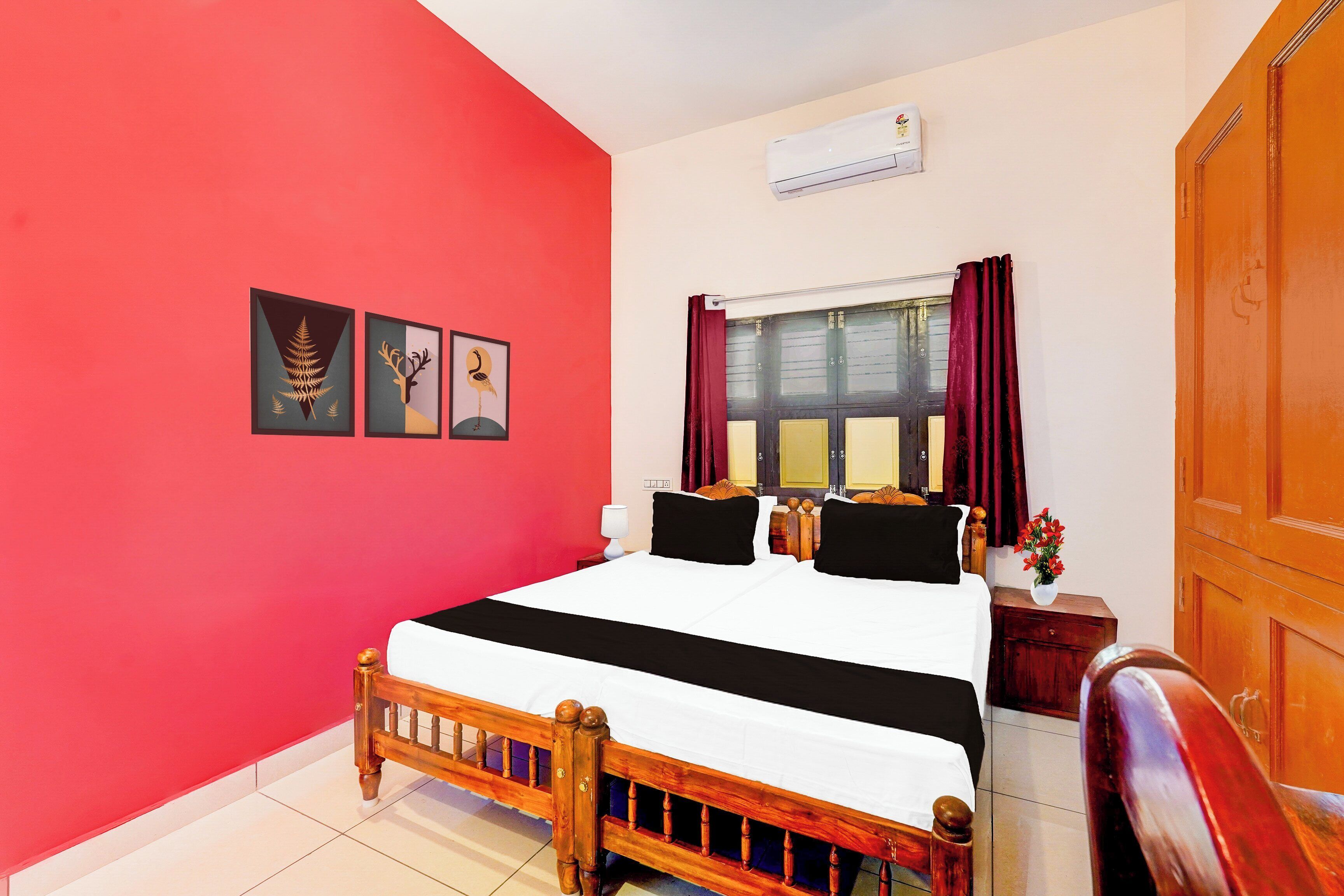 Quarto com cama, janela com cortinas, ar condicionado fixado na parede e quadros emoldurados.