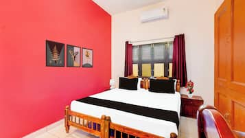 Quarto com cama, janela com cortinas, ar condicionado fixado na parede e quadros emoldurados.