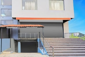 Um edifício moderno com telhado plano, um conjunto de degraus que levam a uma porta de garagem e um corrimão de metal.