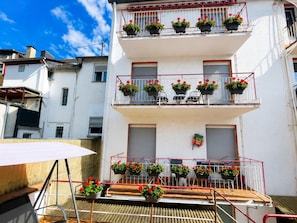 Um edifício com vários andares e varandas, cada uma decorada com vasos de flores.