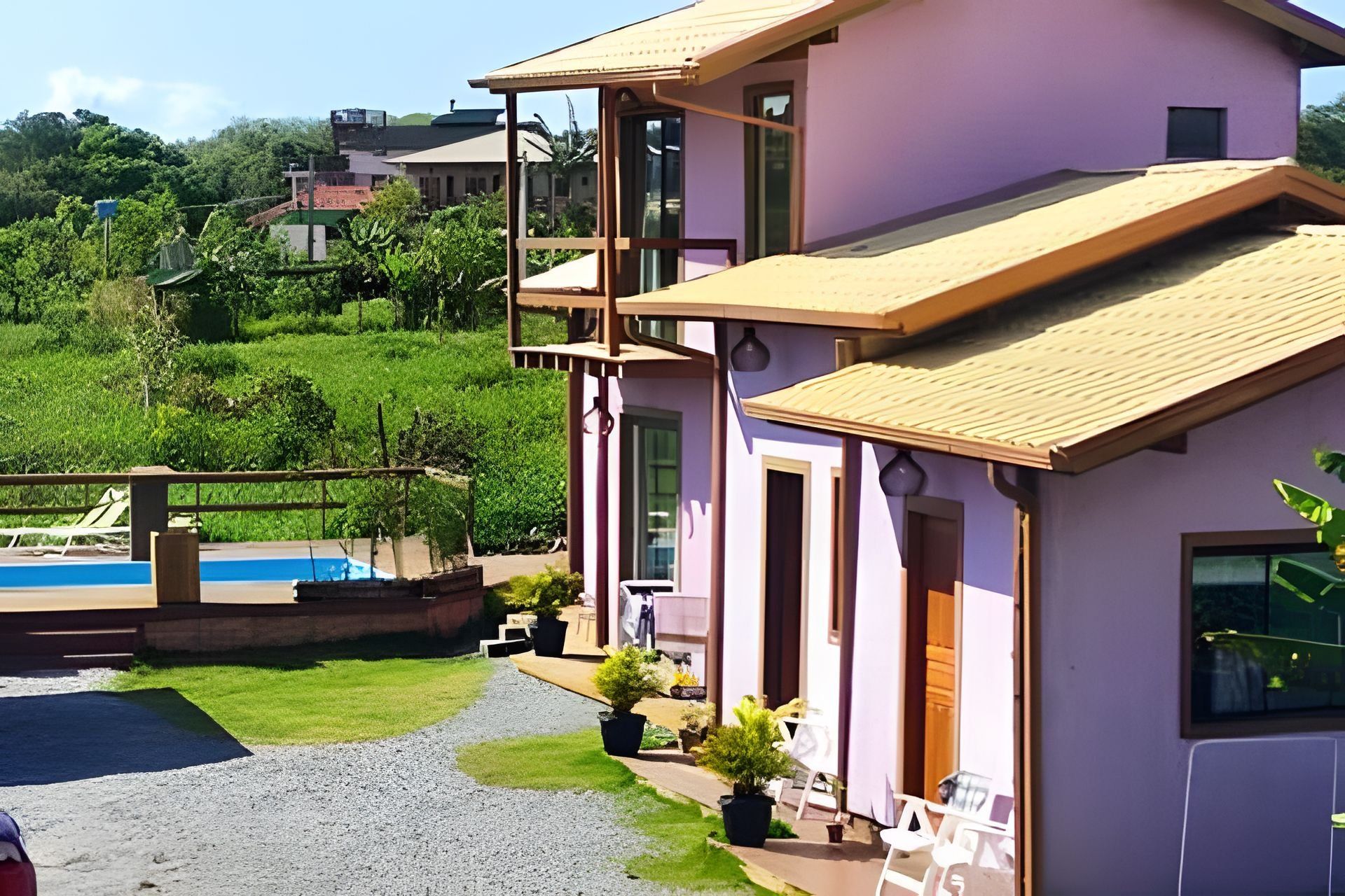 Um edifício de dois andares com piscina, área de estar ao ar livre e jardim.