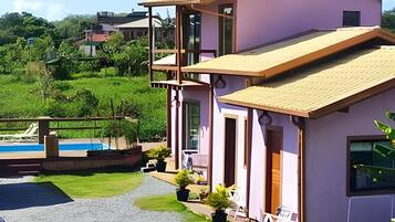 Um edifício de dois andares com piscina, área de estar ao ar livre e jardim.