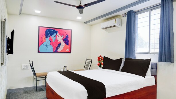 Um quarto com cama, uma cadeira, ar-condicionado na parede, ventilador de teto e uma janela com cortinas.
