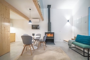 Uma sala de estar moderna com lareira, área de jantar com cadeiras e um sofá.