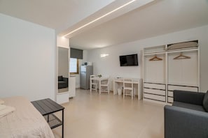 Quarto moderno com cama, escrivaninha, cadeira, televisão e guarda-roupa.