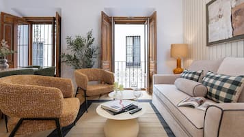 A living room with a sofa, two armchairs, a coffee table, and a balcony with a view.