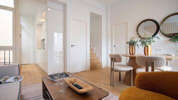 Uma sala de estar moderna com uma mesa de centro de madeira, um sofá e uma área de jantar com cadeiras e uma mesa.