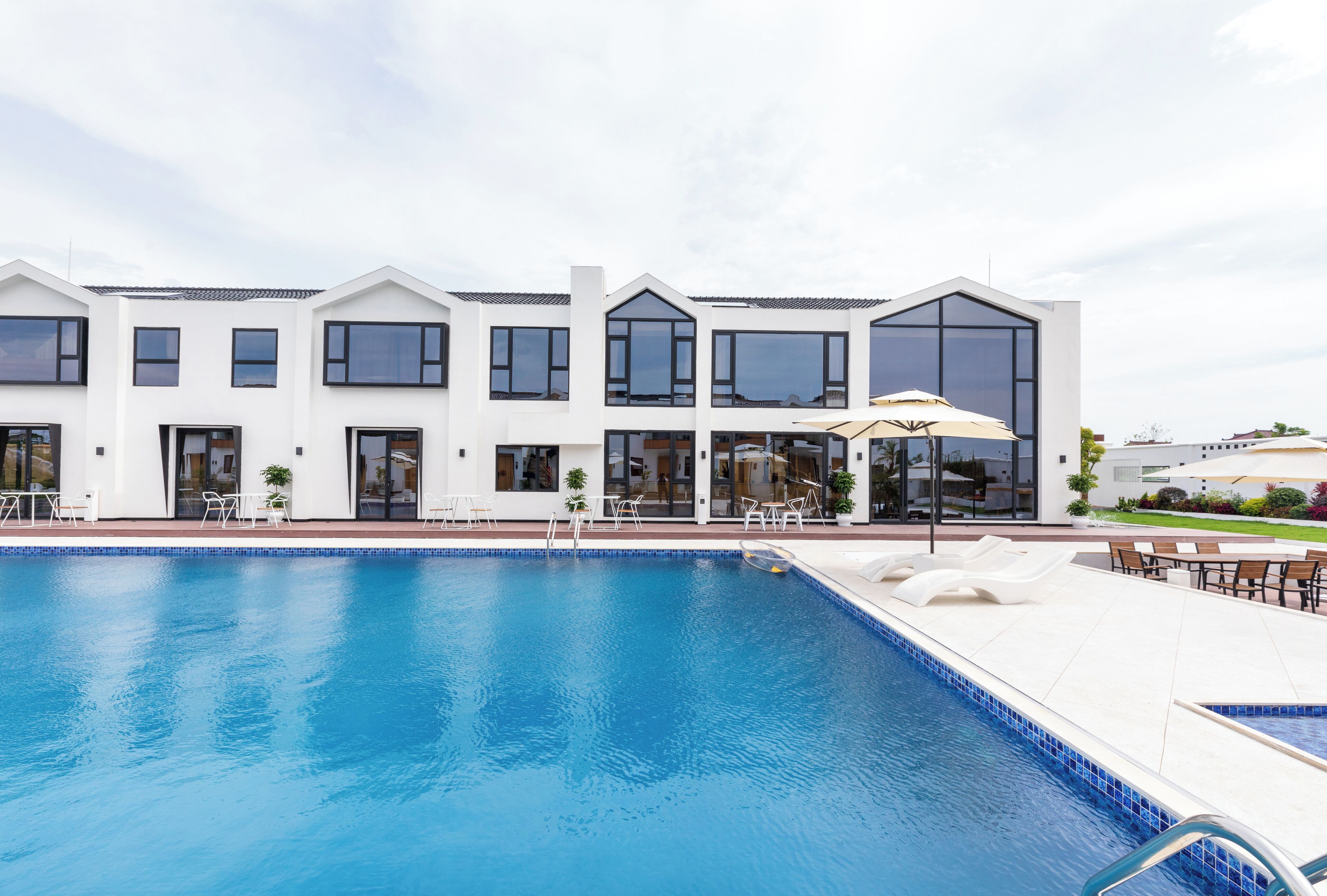 Um edifício moderno com piscina, área de estar externa e grandes janelas.