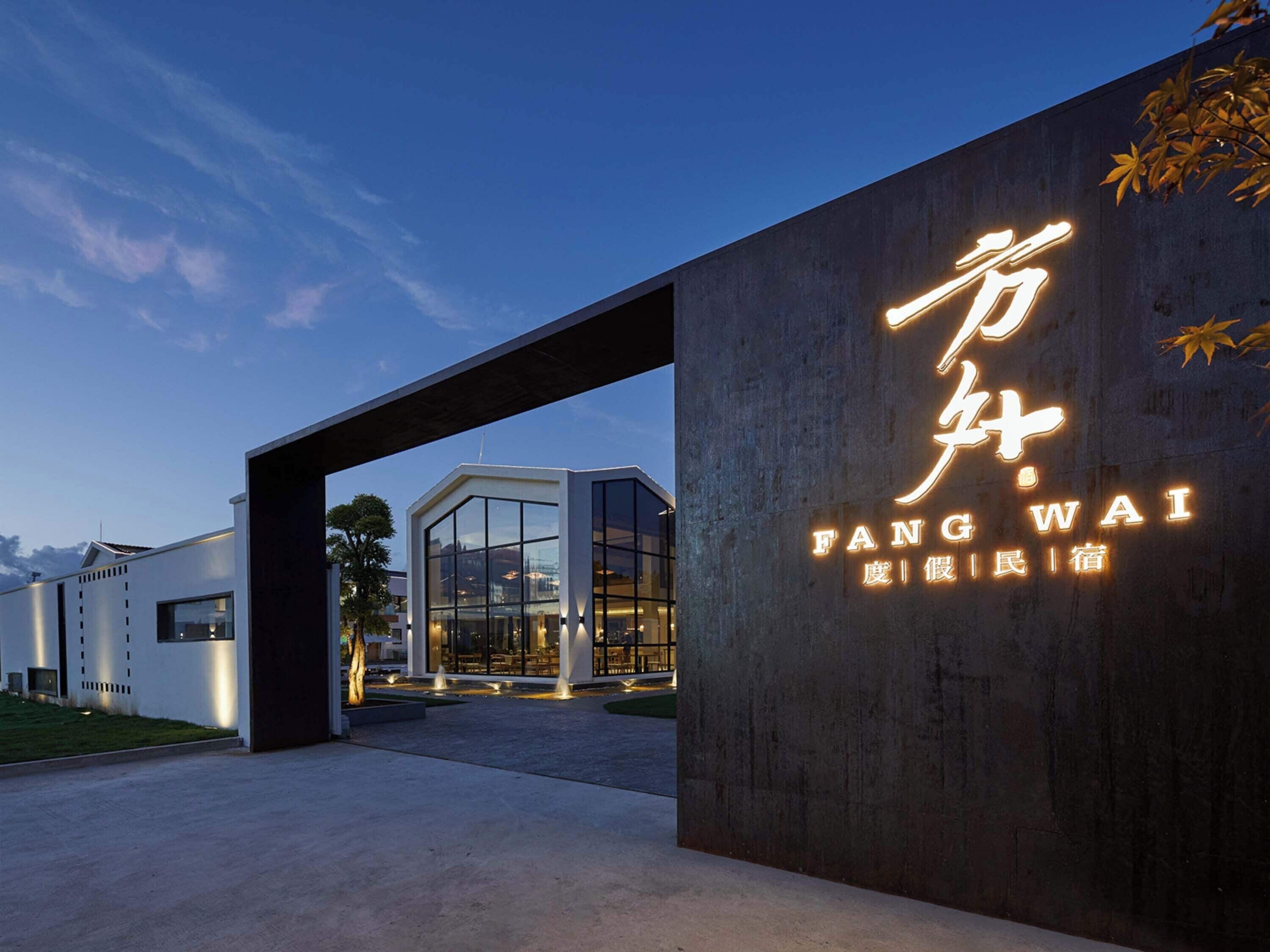 Um edifício moderno com fachada de vidro ampla e um letreiro de neon que diz 'FANG WAI'.
