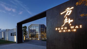 Um edifício moderno com fachada de vidro ampla e um letreiro de neon que diz 'FANG WAI'.