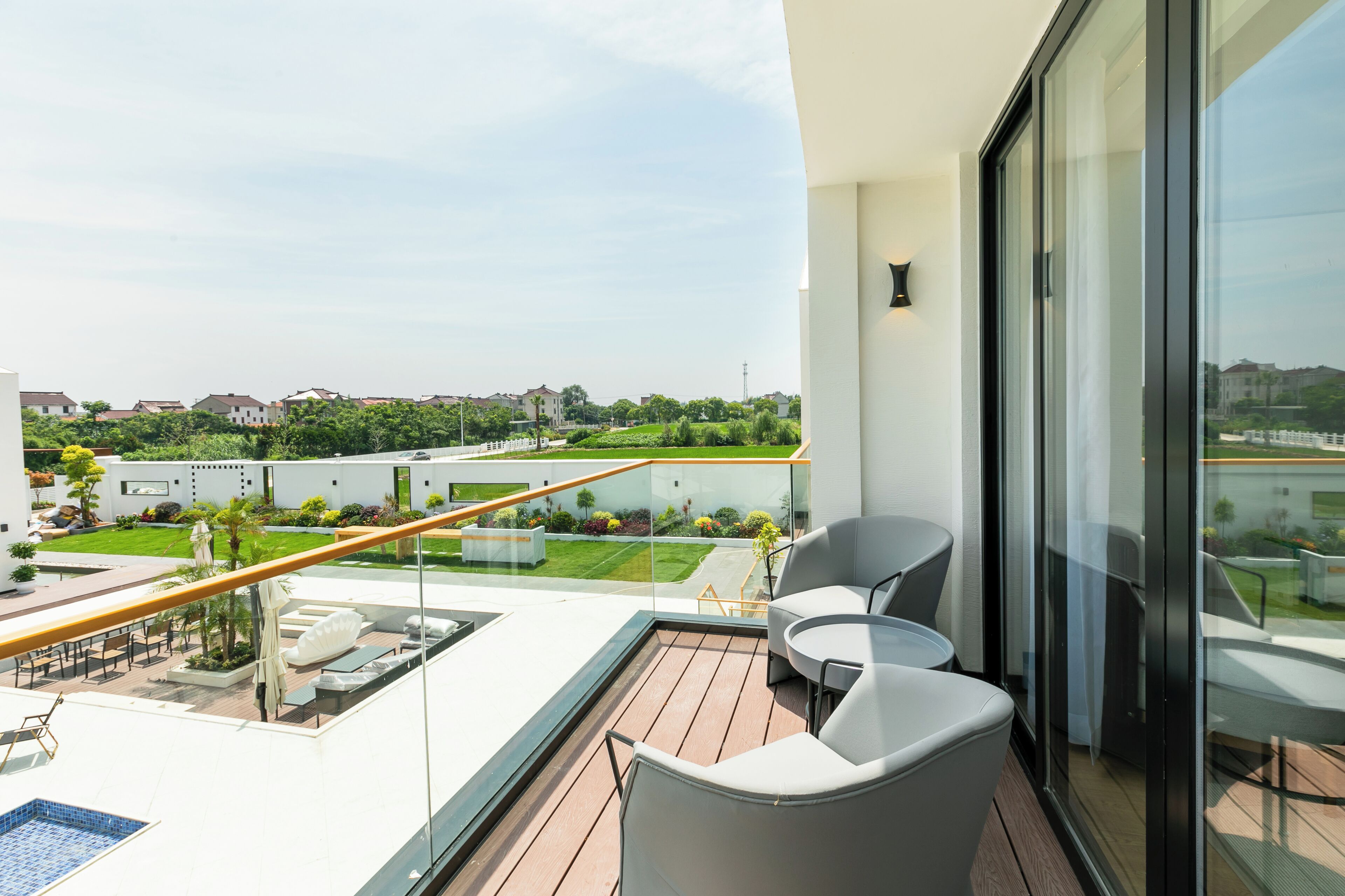 Varanda moderna com piscina, área de estar externa e vista para uma área residencial.