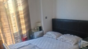 Quarto com cama, mesas de cabeceira e uma janela com persianas.