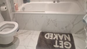 Casa de banho com banheira, sanita e chuveiro.