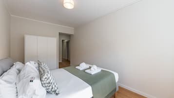 Quarto de hotel com cama, manta verde e toalha branca.
