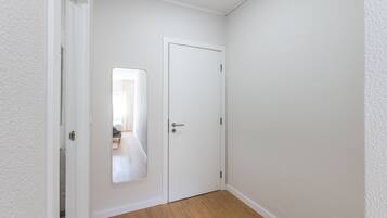 Um corredor estreito com uma porta branca e um espelho na parede.